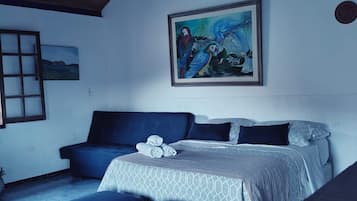Quarto com cama, sofá, quadro e janela.