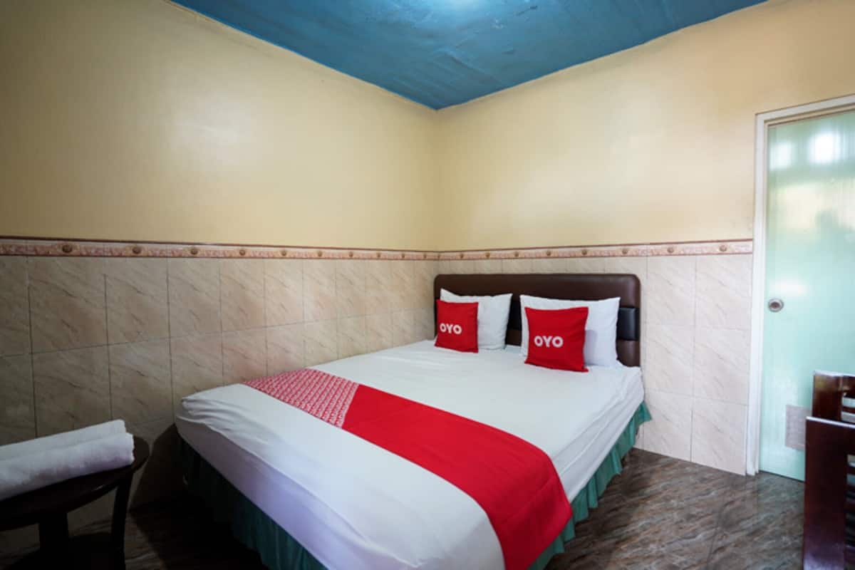 Quarto de hotel com uma cama, uma cadeira e uma porta.