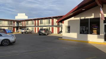 Um estacionamento com vários carros, um edifício com telhado vermelho e uma bandeira americana.
