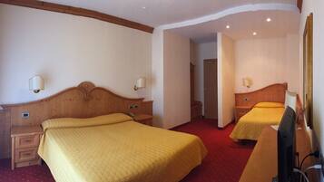 Quarto de hotel com duas camas, cabeceiras de madeira, mesas de cabeceira com luminárias e um tapete vermelho.