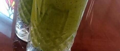 Dois copos de smoothie verde decorados com fatias de kiwi sobre uma mesa de madeira.