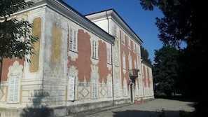 Um edifício histórico com fachada simétrica, combinando tijolo e trabalhos em gesso, e adornado com portadas decorativas.