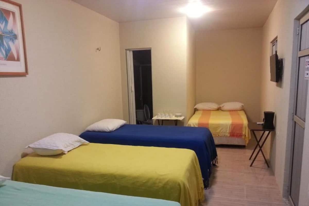 Quarto de hotel com duas camas, uma mesa pequena e uma televisão.