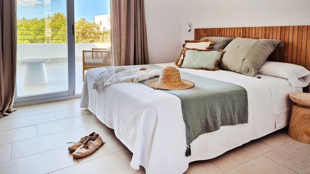 Quarto com cama, varanda e vista para o verde.
