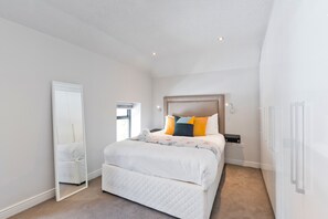 Quarto com cama, espelho, mesa de cabeceira e janela.