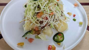 Prato branco com salada sobre mesa de madeira.