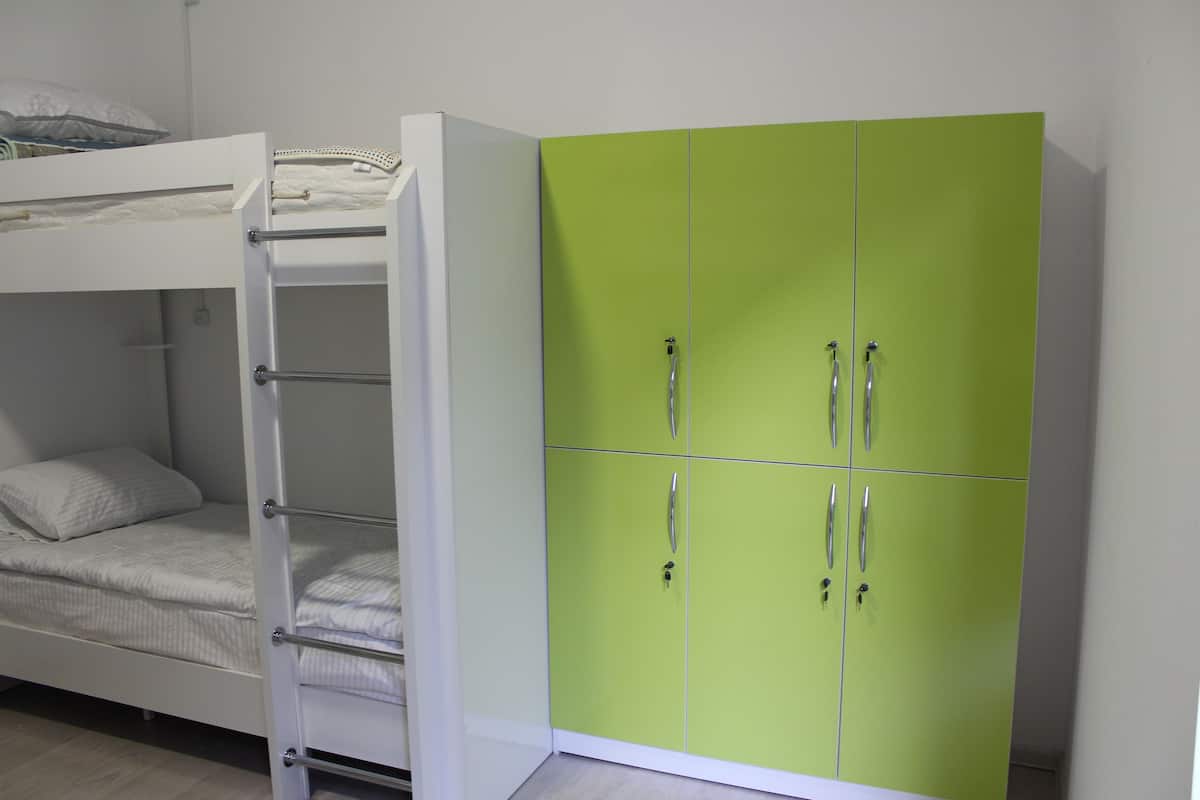 Uma cama box com um guarda-roupa verde ao lado.