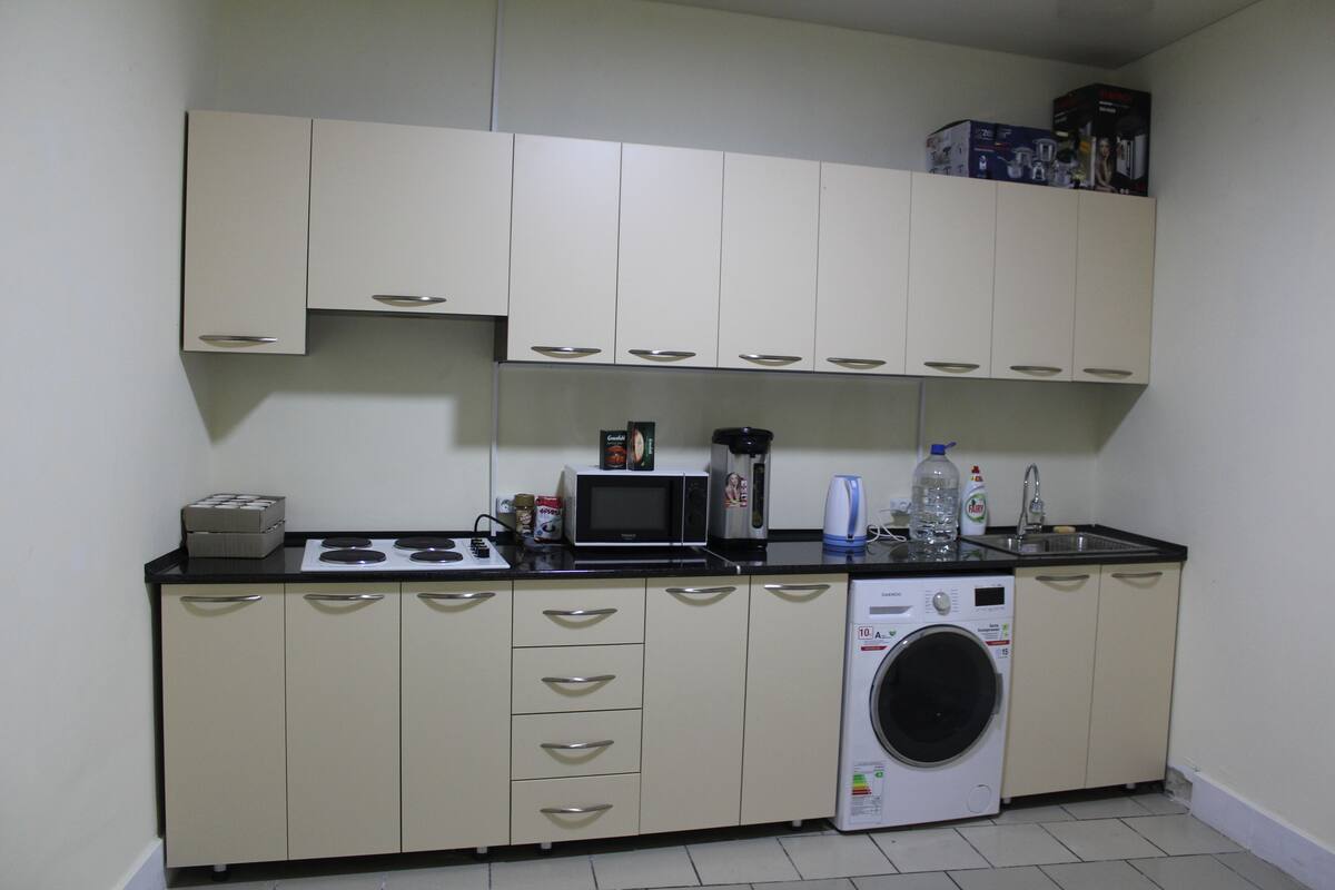 Cozinha compacta equipada com micro-ondas, torradeira e máquina de lavar roupa.
