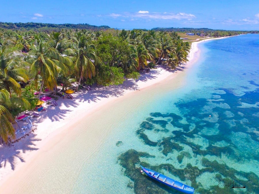 Na praia, areia branca, espreguiçadeiras, guarda-sóis