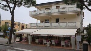 Um edifício de dois andares com café, restaurante e pizzaria no andar térreo.