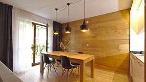 Uma sala de jantar moderna com mesa de madeira, cadeiras pretas e luminárias pendentes.