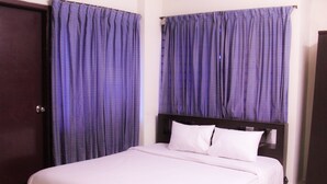 Quarto com cama, cortinas e porta.