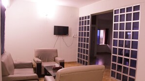 Uma sala de estar com dois sofás, uma mesa de centro e uma televisão de tela plana na parede.