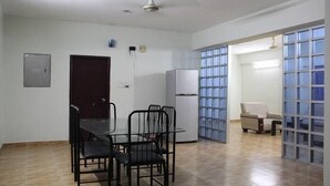 Um quarto com uma mesa de jantar e cadeiras, uma geladeira, uma porta e uma janela com vista.