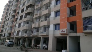 Um edifício residencial com vários andares, varandas, uma placa indicando um hotel e veículos estacionados.