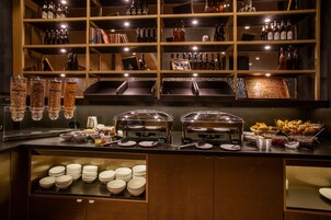 Uma área de buffet com diversas estações de comida, incluindo uma variedade de pratos e bebidas.