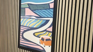 Obra emoldurada retratando uma estrada sinuosa, um carro, uma lua crescente e colinas estilizadas.