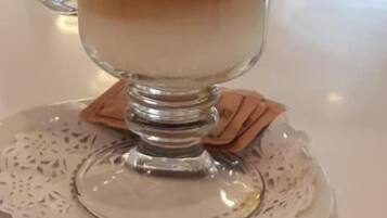 Xícara de café transparente em um pires com um sousplat de renda por baixo.