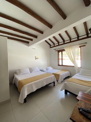 Quarto com duas camas de solteiro, teto de madeira e janela com cortinas.