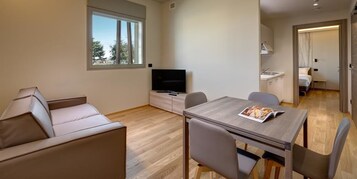 Uma sala de estar moderna com um sofá, uma mesa de jantar e uma televisão.