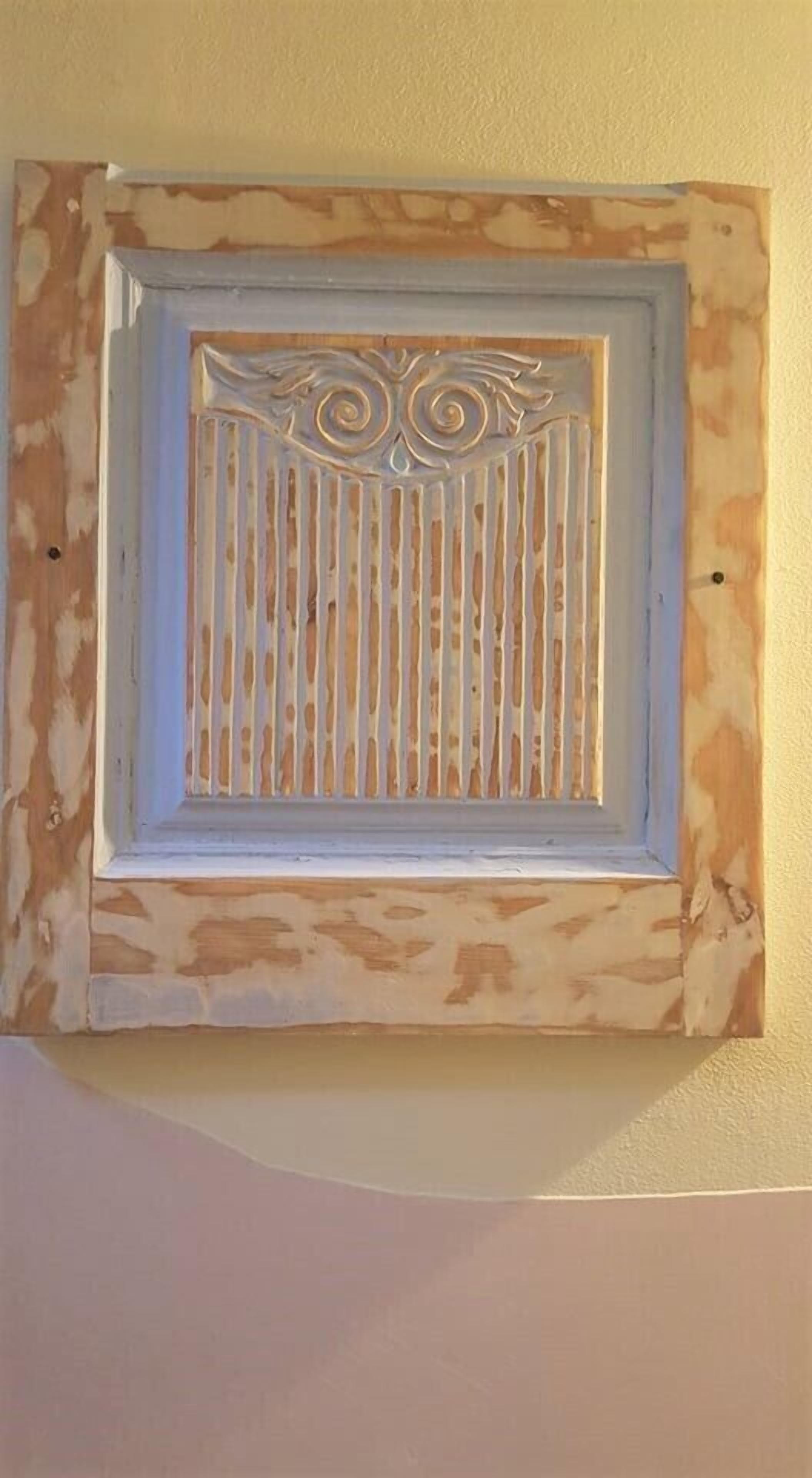 Parede com um painel decorativo com ripas verticais e detalhes ornamentais no topo.