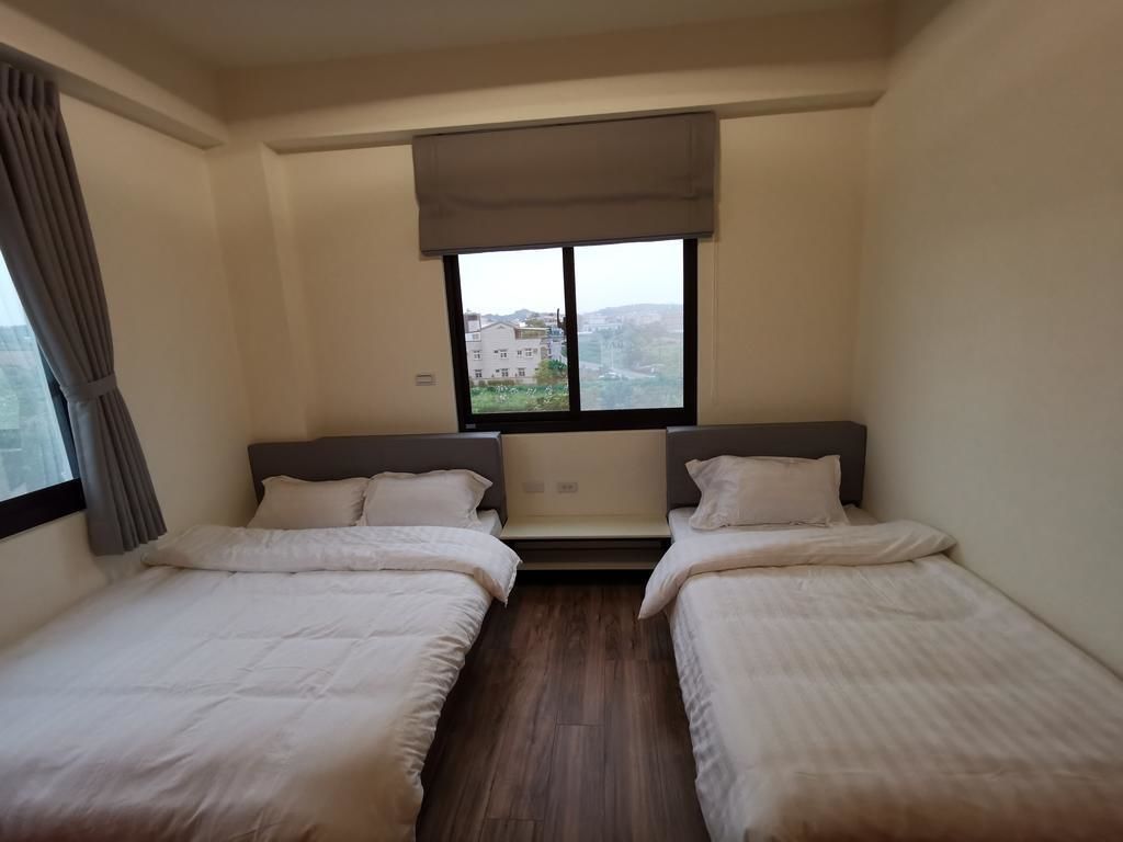 Quarto de hotel com duas camas de solteiro, janela com vista e ventoinha no teto.