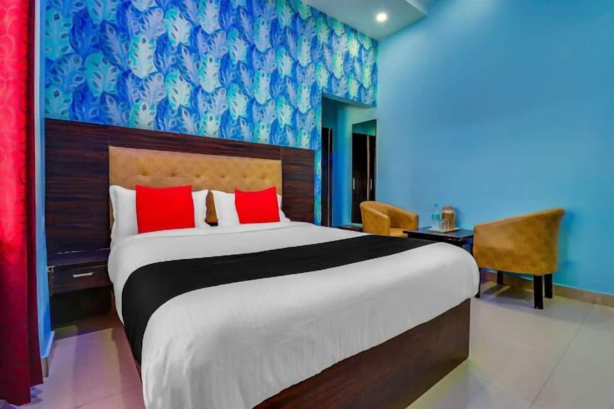 Quarto de hotel com uma cama grande, uma mesa de cabeceira, uma cadeira e parede com padrão azul.