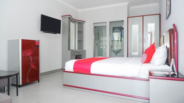 Quarto de hotel moderno com cama, televisão, guarda-roupa e secretária.