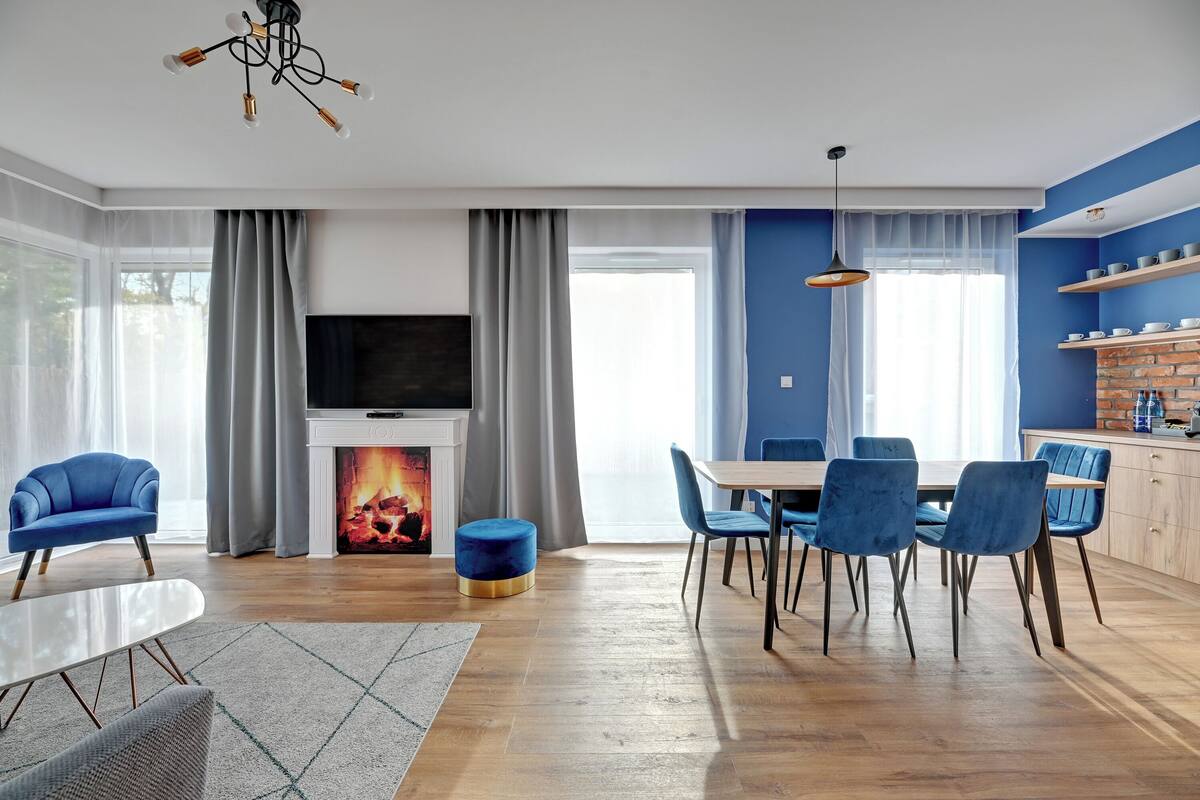 Uma sala de estar moderna com lareira, área de jantar e cozinha.