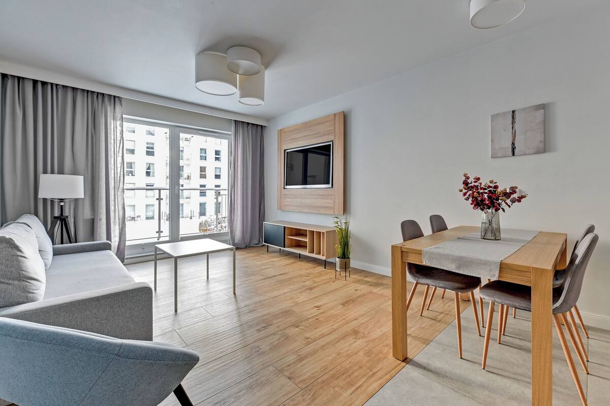 Uma sala de estar moderna com sofá, mesa de jantar e TV.