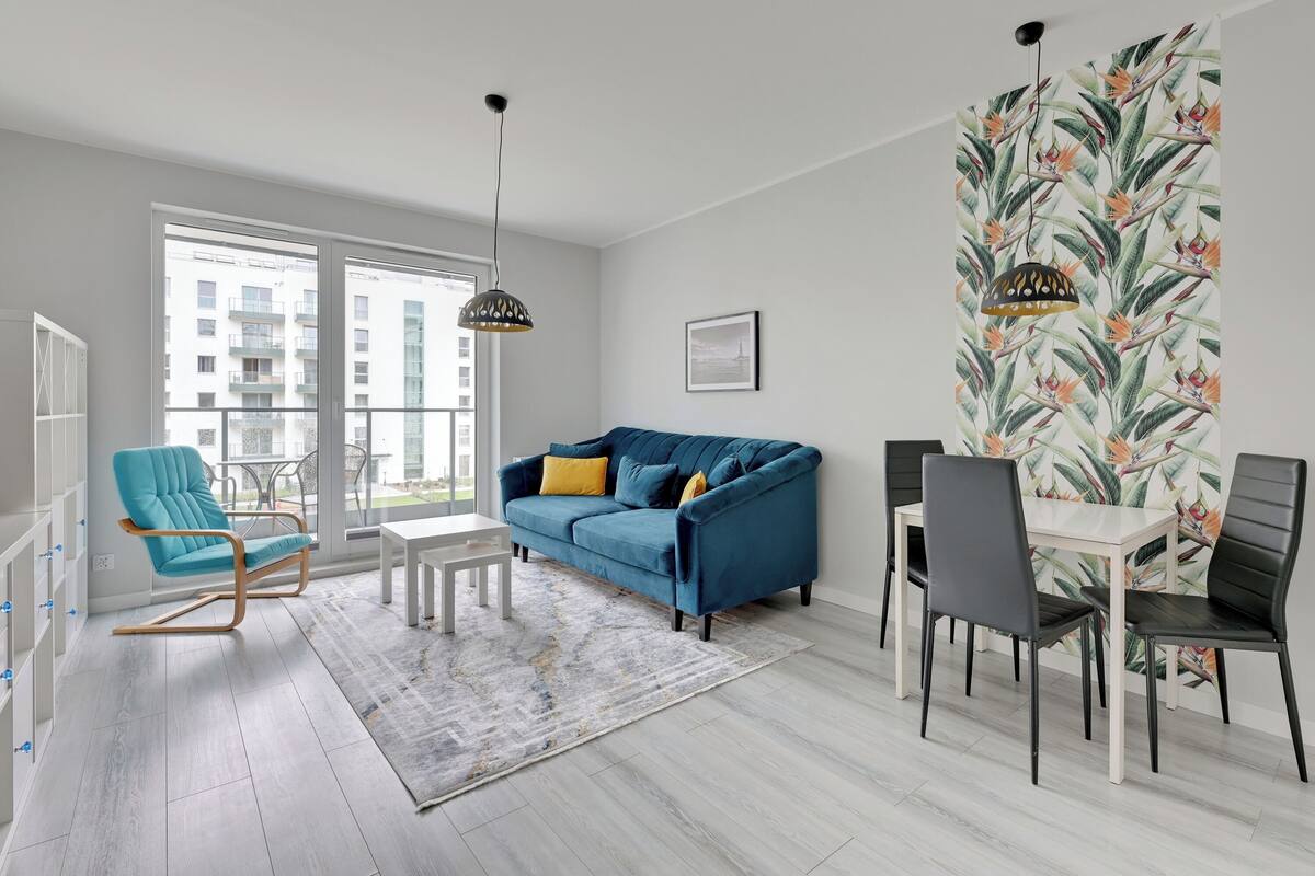 Uma sala de estar moderna com um sofá azul, uma poltrona de balanço e uma mesa de jantar com cadeiras.