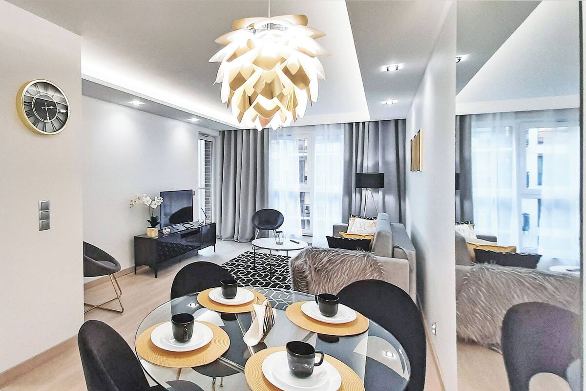 Uma sala de estar moderna com área de jantar, uma janela grande e um lustre.