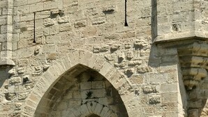 Um arco de pedra que dá entrada a um edifício com piso de azulejos e uma janela visível.