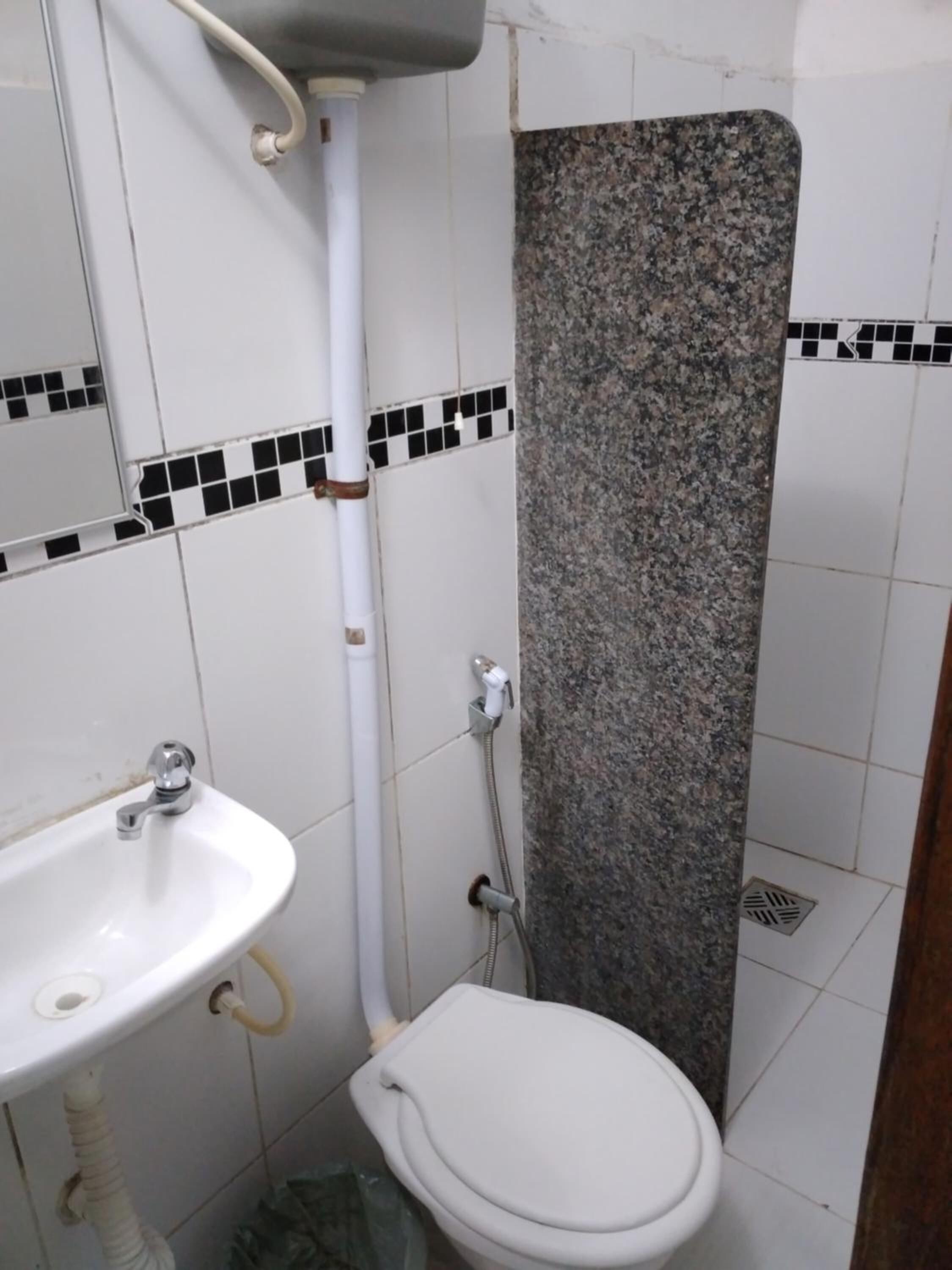 Um banheiro com pia branca, vaso sanitário e box de chuveiro.