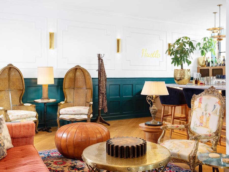 Um quarto com uma parede em tom de verde-água, um letreiro 'Hustle', um espaço de bar com garrafas e móveis clássicos.