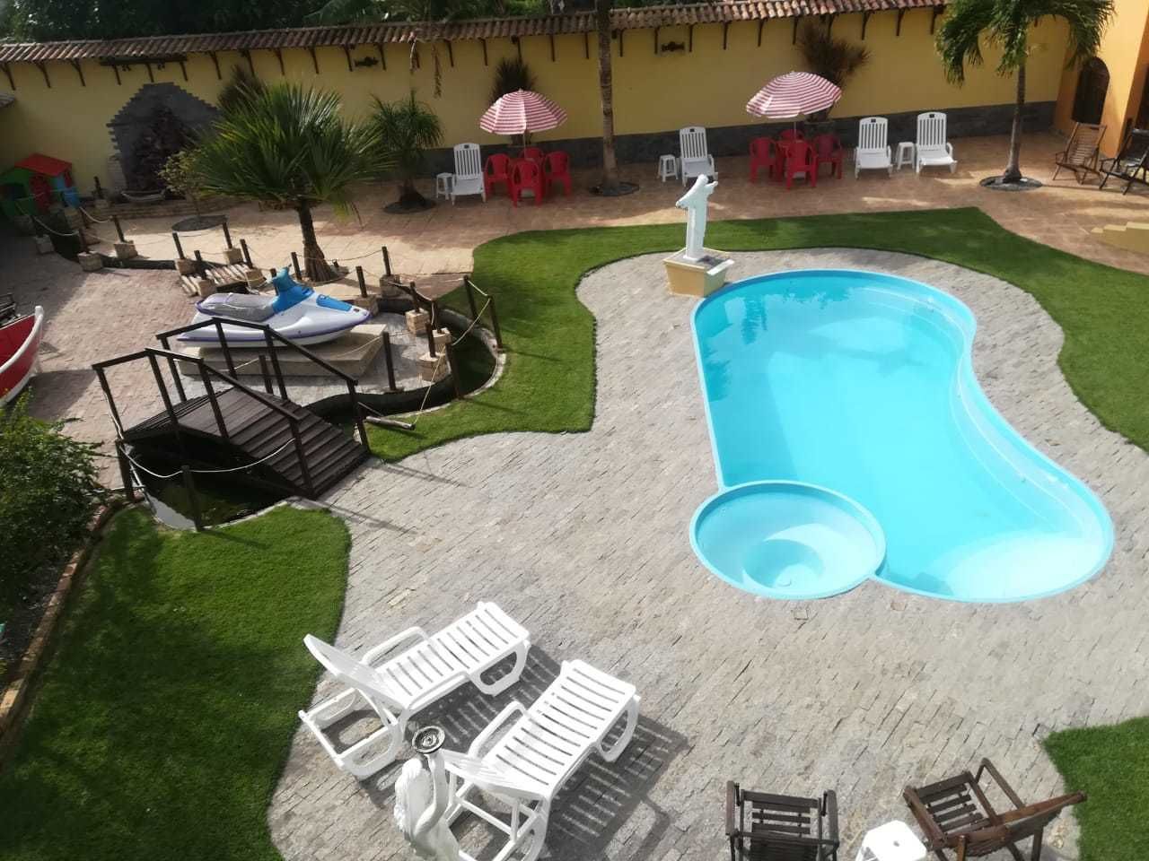 Um quintal com piscina, um pequeno deck e área de estar ao ar livre.