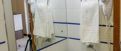 Casa de banho com lavatório, espelho, secador de cabelo e porta-toalhas.