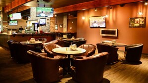 Restaurante com assentos de couro, área de bar e várias televisões exibindo esportes.