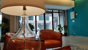 Um hall com uma grande luminária de vidro, poltronas de couro e uma parede verde-água.