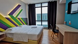 Quarto de hotel moderno com uma cama grande, uma escrivaninha e vista da cidade através de amplas janelas.