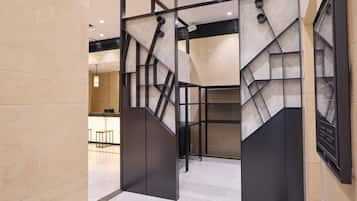 Um interior moderno com uma mesa de recepção, divisória de metal preto e piso revestido de azulejos.