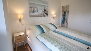Quarto com cama, luminárias de cabeceira, mesa de cabeceira, pintura e decoração de parede em madeira.
