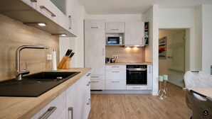 Cozinha moderna com bancada de madeira, eletrodomésticos de aço inoxidável e forno embutido.