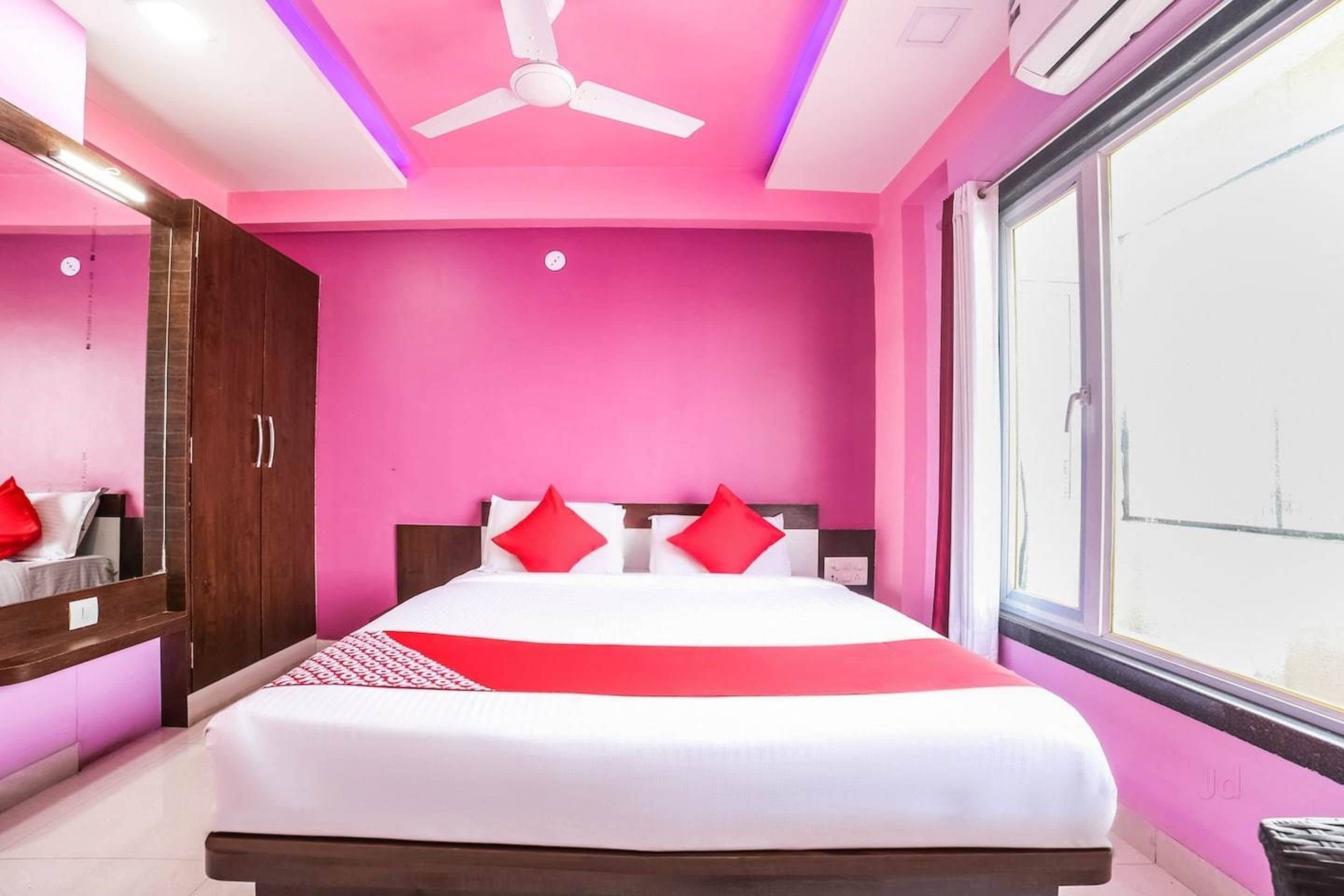 Quarto com cama, ventilador de teto, guarda-roupa e uma janela grande.
