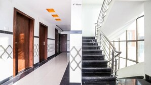 Corredor de hotel com escada que leva ao quarto andar.