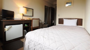 Quarto de hotel com cama, escrivaninha, computador, televisão e frigorífico.
