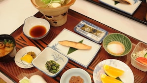 Uma refeição tradicional japonesa com diversos pratos e utensílios sobre um tapete de tatame.