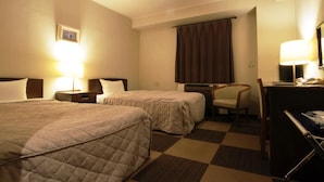 Quarto de hotel com duas camas, uma escrivaninha, uma cadeira e uma televisão.