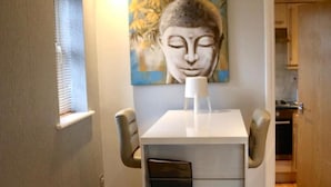 Quarto com escrivaninha branca, grande estátua de Buda e pintura de Buda na parede.