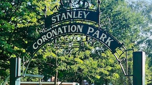Uma placa de metal com as palavras 'Stanley Coronation Park' em letras brancas sobre fundo preto.